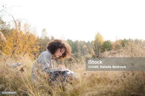 햇빛에 젊은 예쁜 혼합 인종 십대 학생 소녀 야외 행복한 여자는 강둑에 앉아 가을에 노트북에 기록 14 15 살에 대한 스톡
