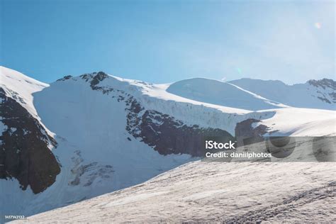 햇빛에 큰 빙하와 미니멀 한 산 풍경 빙하 혀와 간단한 눈 미니멀리즘 화창한 날에는 푸른 하늘 아래에서 매우 높은 고도에서 눈산 꼭대기까지 최소한의 알프스 경관을 볼 수
