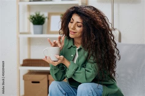 Happy Cute Enjoyed Pretty Tanned Curly Latin Lady Look With Love Aside Hold Cup Of Tea Coffee In