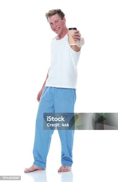 2029세의 풀 길이 1인용 잘생긴 사람 짧은 머리 백인 남성 젊은 남성 앞의 흰색 배경 착용 잠옷 탱크 탑을 마시고 웃고 쾌활 하 고 커피 컵 컵을 들고 20 29세에