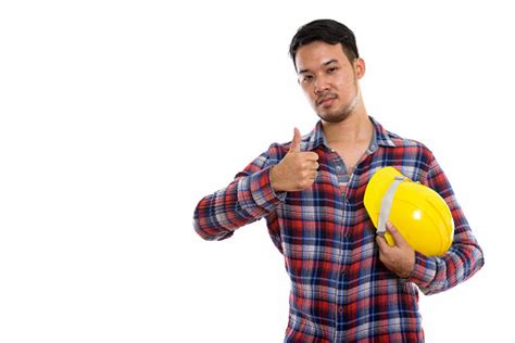 엄지손가락을 포기 하는 동안 안전 헬멧을 들고 젊은 아시아 남자 건설 노동자의 스튜디오 샷 20 29세에 대한 스톡 사진 및 기타 이미지 20 29세 25 29세