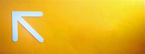 흰색 화살표 기호는 복사 공간이 있는 노란색 콘크리트 벽의 위 입구 출구 또는 길을 가는 방향을 알려줍니다 벽에 대한 스톡 사진