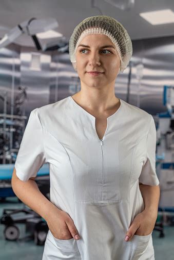 파란색 코트를 입은 여성 의사가 청진기와 알약을 손에 들고 수술중인 동안 서 있습니다 20 29세에 대한 스톡 사진 및 기타