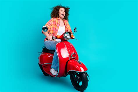 유쾌한 젊은 여성이 청록색 배경의 빨간 스쿠터를 타고 라이프 스타일과 행복을 보여줍니다 25 29세에 대한 스톡 사진 및 기타 이미지 25 29세 갈색 갈색 머리