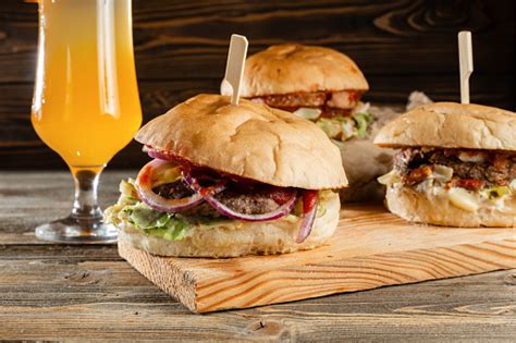 바베 큐 석탄에 고기를 요리 한 3 개의 큰 버거 나무 배경에 주스 한잔과 함께 점심 패스트 푸드와 건강에 해로운 음식의 개념 3가지 개체에 대한 스톡 사진 및 기타 이미지