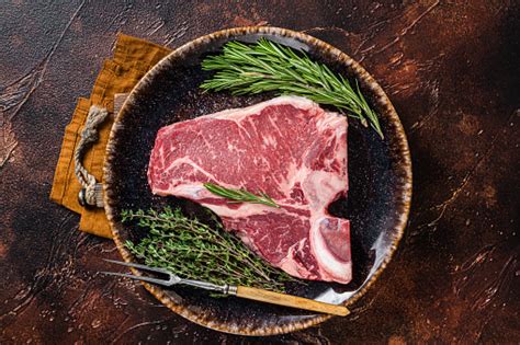 건조 숙성 생 포터 하우스 쇠고기 고기 스테이크 향신료와 소박한 접시에 신선한 T 뼈 어두운 배경 위쪽 보기 0명에 대한 스톡