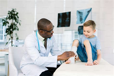 아프리카 남자 의사 응급 처치는 탄력 붕대로 어린이 소년 환자의 다리 염좌를 검사합니다 사진 Unsplash의 흑인 소년 이미지