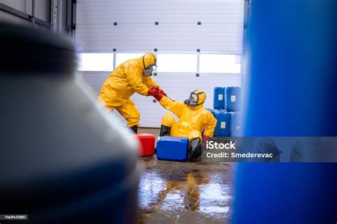화학 공장 사고 미끄러운 바닥 유출 된 화학 물질 보호 위험 물질 정장을 입은 작업자는 동료가 넘어진 후 일어설 수 있도록 도와줍니다 2명에 대한 스톡 사진 및 기타 이미지
