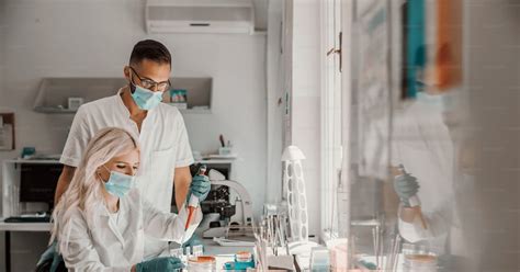 얼굴 마스크와 고무 장갑을 낀 매력적인 헌신적인 금발 여성 실험실 조수가 코로나 바이러스 치료법을 연구하고 있습니다 그녀