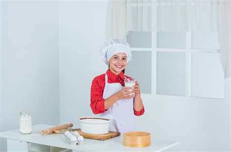 우유 한 잔 부엌에서 요리하는 행복한 아이 부엌에서 쿠키를 굽습니다 전문적이고 숙련 된 베이커 요리사 유니폼과 모자를 쓴 아이