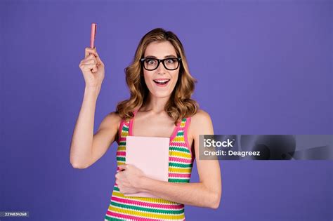 화려한 옷차림을 한 여자가 생생한 보라색 배경에 쾌활한 표정으로 공책과 펜을 들고 있습니다 20 24세에 대한 스톡 사진 및 기타 이미지 Istock