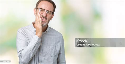 잘생긴 중간 나이 우아한 수석 남자는 치아에 치 통 이나 치과 질환 때문에 고통 스러운 표정으로 입에 접촉 고립 된 배경 위에 안경을 착용 치과 의사 개념입니다 건강관리와