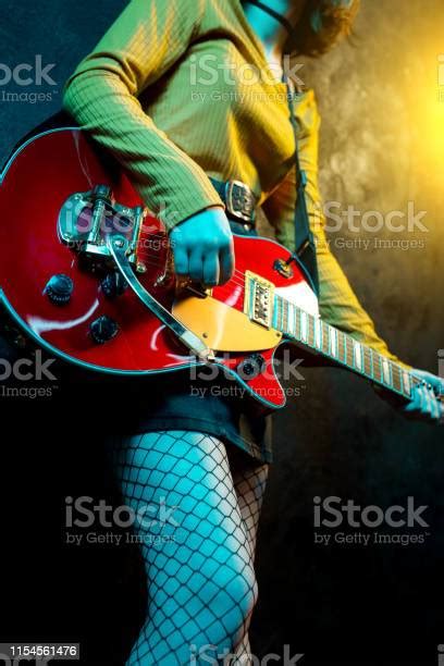 네온 불빛에 젊은 소식통 여자 다리와 레드 기타의 클로즈업 사진 록 뮤지션은 일렉트릭 기타를 연주하 고 있습니다 90 년대 스타일의 개념입니다 가수에 대한 스톡 사진 및