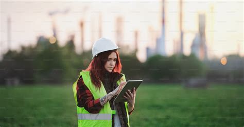 안전모와 태블릿을 쓴 젊은 여성 엔지니어가 정유 공장 옆에 서 있습니다 공간을 복사합니다 사진 Unsplash의 연료 및 발전 이미지