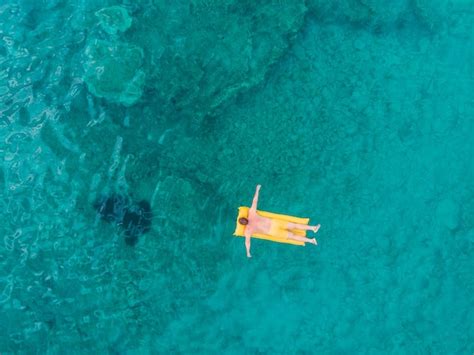 Premium Photo Man On Yellow Inflatable Mattress In Clear Sea Water