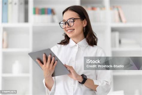 흰 셔츠와 안경을 쓴 멋진 젊은 백인 사업가가 사무실 인테리어에서 태블릿으로 채팅하고 있습니다 20 24세에 대한 스톡 사진 및 기타 이미지 Istock