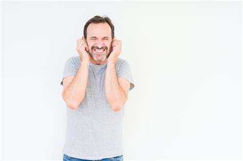 시끄러운 음악의 소음에 대 한 짜증이 식이 손가락으로 귀를 덮고 격리 된 배경 위에 잘생긴 수석 남자 청각 장애인 개념입니다