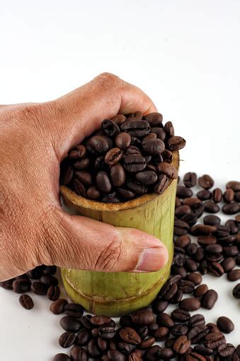 손이 커피 원두와 커피 원두가 흰색 배경에 흩어져있는 대나무 머그잔을 집어 들고 있습니다 갈색에 대한 스톡 사진 및 기타 이미지 갈색 구이 그런지 이미지 기법
