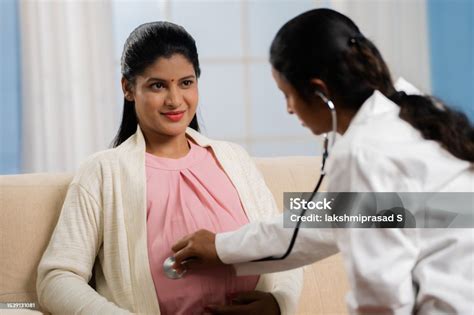 집에서 청진기를 사용하여 임산부 배의 아기 움직임을 검사하는 인도 의사의 어깨 샷 가정 건강 검진 임신 관리 및 치료의 개념