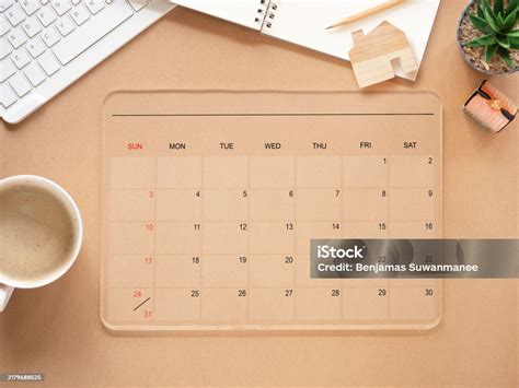 평면도 키보드로 이달의 화면을 보여주는 투명 태블릿의 온라인 캘린더 앱 갈색 테이블에 커피 머그잔을 사용하여 매주 설정하고 설정된 목표를 달성하기 위한 월간 목표를