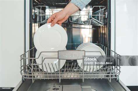 식기 세척기를 식기로 접시에 담거나 비우거나 내리는 여성 손 주방용품 라이프스타일 전망 여자는 접시를 식기 세척기에 넣거나 꺼냅니다 주부는 집안일을한다 식기세척기에 대한