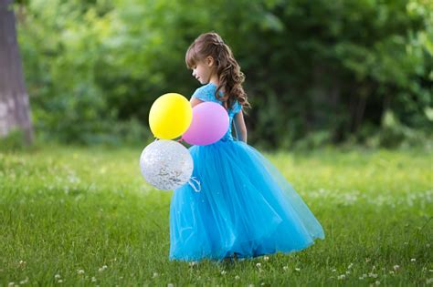 프로필 예쁜 작은 금발 긴 머리 소녀의 전체 길이 초상화 는 흐린 녹색 나무 배경에 피는 필드에 서 화려한 풍선 긴 파란색