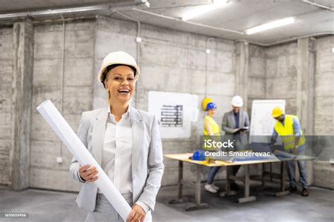 건물 계획과 청사진을 가진 여성 구조 엔지니어가 건설 현장에 서 있고 동료들은 배경에서 브레인스토밍을 하고 있다 건설 산업에 대한 스톡 사진 및 기타 이미지 Istock