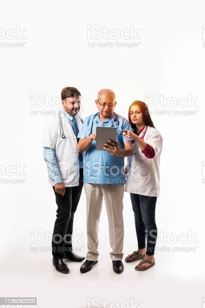 성공적인 인도 의사의 그룹 태블릿 무선 컴퓨터 기술을 사용 하 여 흰색 배경 위에 고립 서 있는 동안 선택적 초점 다민족 그룹에