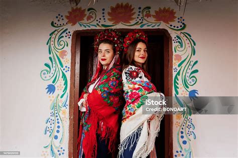 전통적인 민족 의상을 입은 두 명의 우크라이나 여성과 장식된 오두막을 배경으로 한 꽃 붉은 화환 우크라이나 국가 수 놓은 드레스는 Vyshyvanka를 호출합니다