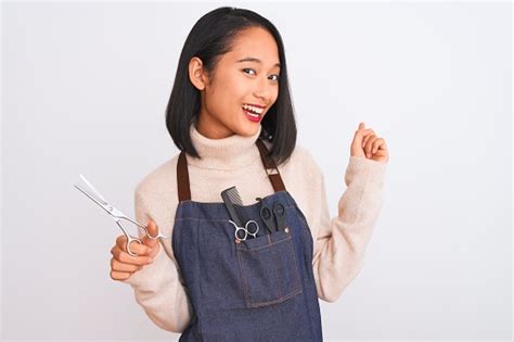 중국 미용사 여자 에이프런 을 입고 가위를 들고 고립 된 흰색 배경 매우 행복 가리키는 손과 손가락 으로 측면에 헤어 스타일리스트에 대한 스톡 사진 및 기타 이미지 Istock