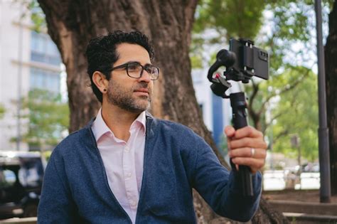 Premium Photo Middleaged Man Using A Gimbal To Record Something Offcamera With His Cell Phone