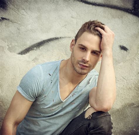 Jeune Homme Beau Avec Se Reposer Déchiré De Jeans Extérieur Image Stock