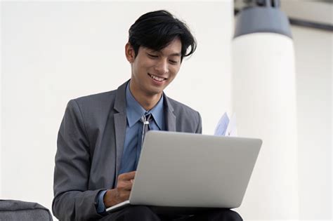 현대적인 야외 비즈니스 환경에서 노트북으로 작업하면서 미소 짓고 있는 젊은 아시아 사업가 Office For National Statistics에 대한 스톡 사진 및 기타