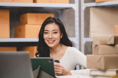 온라인 쇼핑 개념 행복한 젊은 아시아 비즈니스 소유자 여성 소포 상자를 준비하고 집에서 노트북 컴퓨터로 고객에게 배달하기위한 제품 주문을 확인 사이버 공간에서 전자 비즈니스