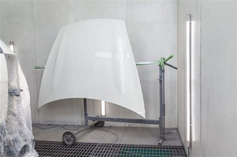 특수 챔버에서 자동차를 그림에 대 한 워크샵에서 특수 홀더에 장착 퍼 티의 도움으로 사고 후 흰색 차의 큰 후드의 수리 밝은 조명과 함께 부스 스프레이 가리기에 대한 스톡