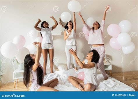 Happy Diverse Girls Playing With Balloons In Bedroom At Party Stock