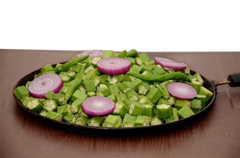 흰색 갈색 배경에 고립 된 프라이팬에 잘 익은 녹색 슬라이스 레이디 핑거 양파 잘 익은 녹색 쌀쌀한 무리를 닫습니다 건강한 생활