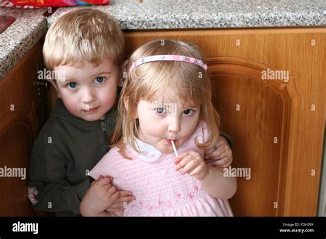 Blonde Hair Brown Eyes Brother And Sister Enjoying A Lolly Hugging Two