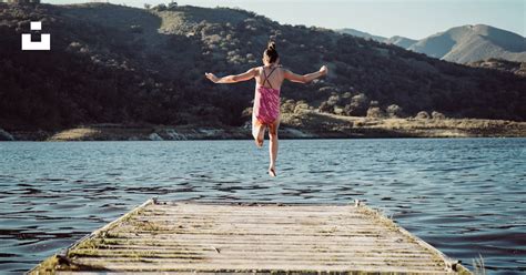 낮에 물을 향해 점프하는 분홍색 상의를 입은 여자 사진 Unsplash의 무료 바다 이미지