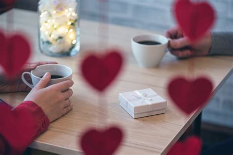 발렌타인 레스토랑에서 축하하는 여자와 남자의 클로즈업 남자 친구 주는 작은 흰색 선물 상자 에 여자 친구 하트 모양의 화환을 통해 볼 수 있습니다 사랑 로맨스 날짜 2명에