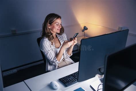Woman Typing Text Message Using Smart Phone While Working Late Stock