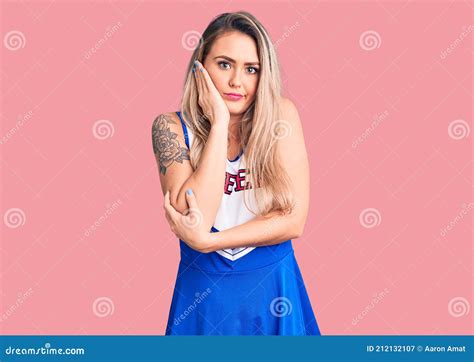 Young Beautiful Blonde Woman Wearing Cheerleader Uniform Thinking