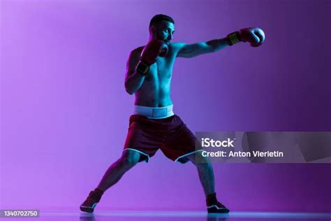 네온 빛에 보라색 배경 위에 고립 된 빨간색 유니폼 훈련에서 한 전문 복서의 측면 보기 전체 길이 초상화 스트레이트 펀치 이동 20 24세에 대한 스톡 사진 및 기타 이미지