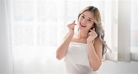 젊은 아름다운 아시아 여성의 초상화는 침대 룸 여름철에 심장 모양으로 제스처를 손짓합니다 미소 얼굴 아시아 소녀는 캐주얼 천을 착용합니다 일본 여자 라이프 스타일 사랑스러운