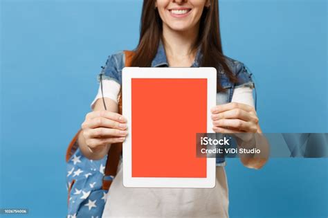 배낭에 파란색 배경에 고립 된 빈 검은색 빈 화면으로 태블릿 Pc 컴퓨터를 들고 웃는 젊은 갈색 머리 여자 학생을 잘립니다 대학에서 교육입니다 광고에 대 한 공간을 복사