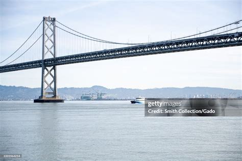 View Of A Commuter Ferry Passing Beneath The Bay Bridge On A Clear
