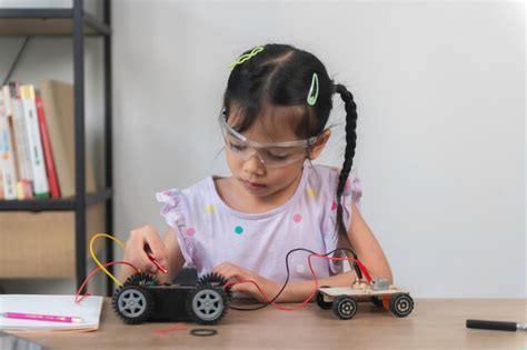 premium photo asian littlle girl constructing and coding robot at