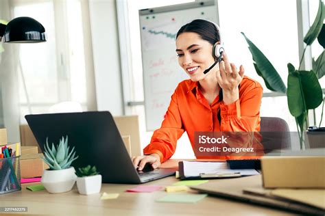 헤드셋을 착용한 젊은 여성 기업가가 사무실 환경에서 노트북으로 작업하고 전자 상거래 소매업을 관리하고 있습니다 20 24세에 대한 스톡 사진 및 기타 이미지 Istock