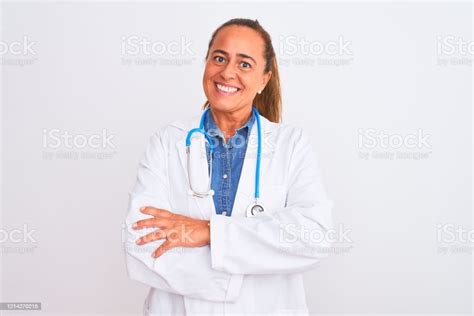 중년 성숙한 의사 여자 는 고립 된 배경 위에 청진기를 입고 행복한 얼굴 카메라를 보고 교차 팔로 미소 긍정적 인 사람 갈색