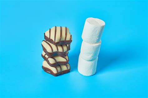줄무늬 흰색과 다크 초콜릿 캔디의 힙은 별모양과 마시멜로 모양의 실린더 형태로 파란색 조리대에 놓여 있습니다 클로즈업 갈색에 대한 스톡 사진 및 기타 이미지 Istock